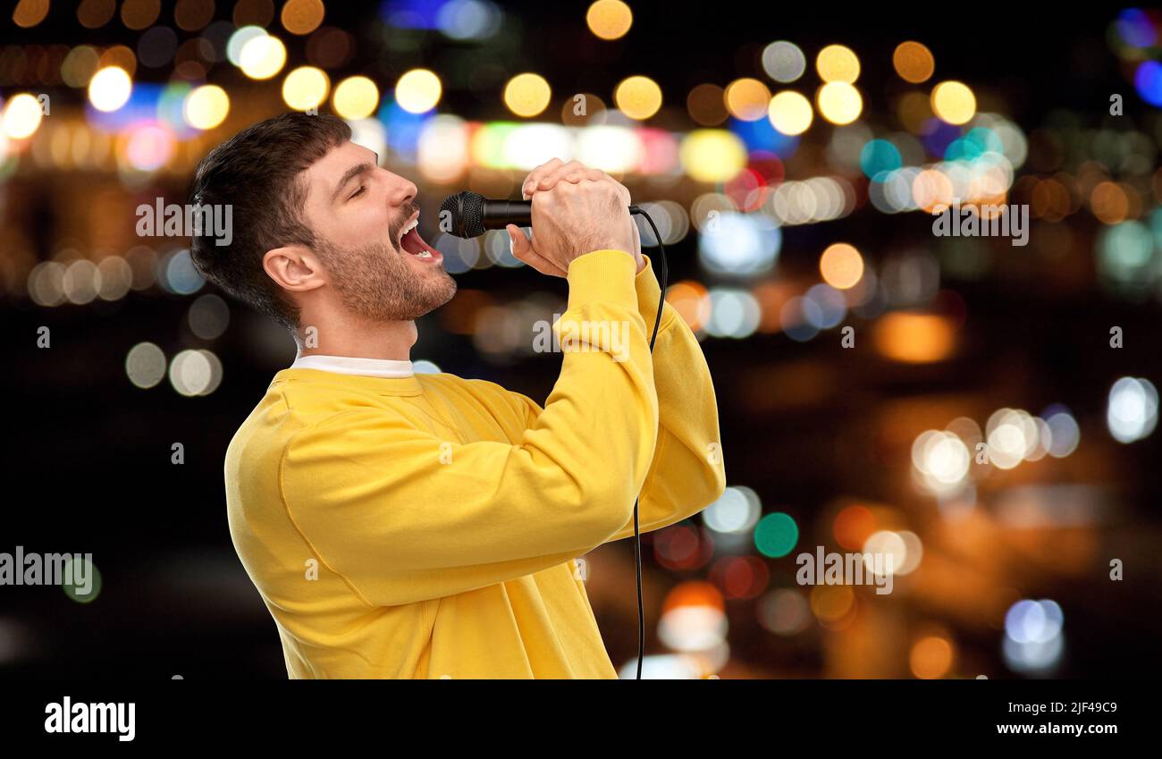 man with microphone singing over night city lights Stock Photo - Alamy