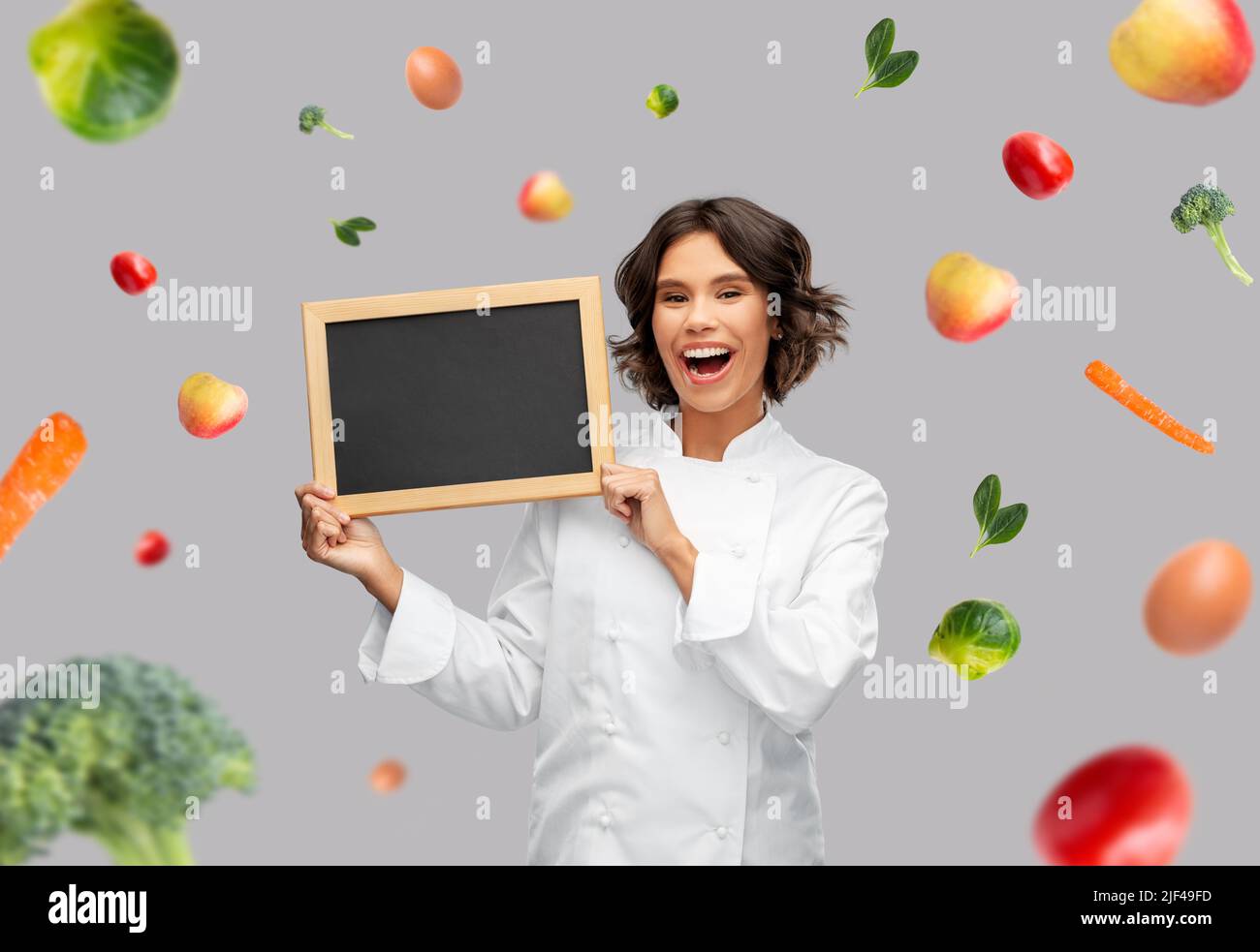 happy female chef holding chalkboard over food Stock Photo - Alamy