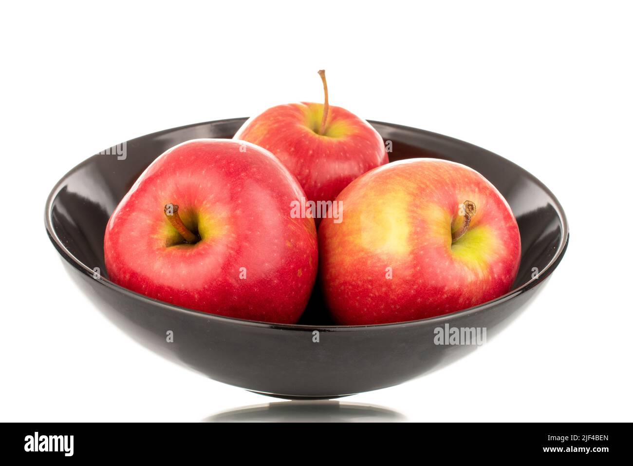 Three juicy red apples in a black ceramic plate, close-up, isolated on ...