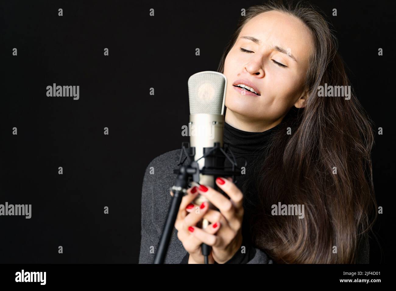 Young Asian or Caucasian woman singing song to microphone in music ...