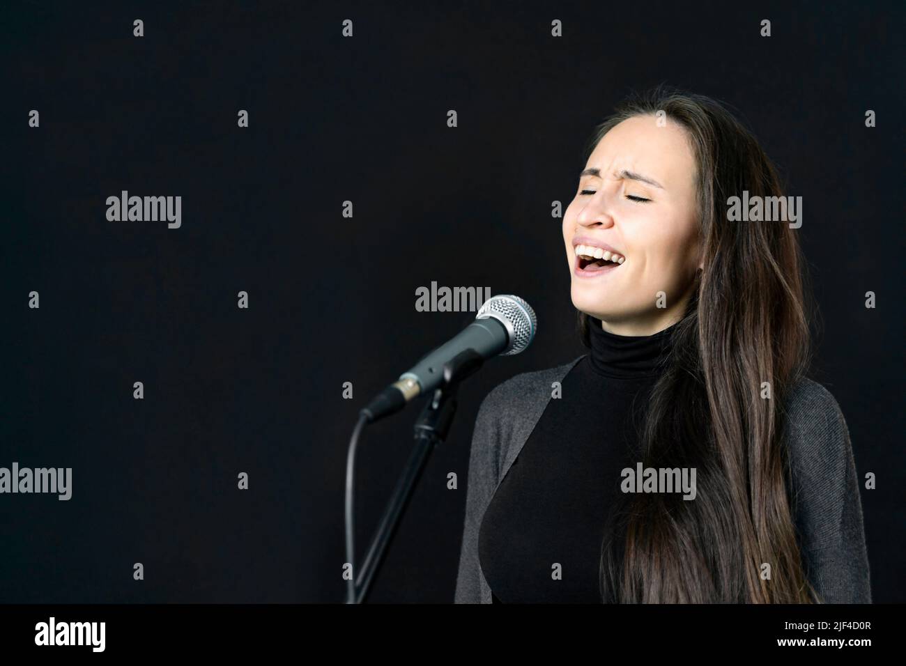 Young Asian or Caucasian woman singing song to microphone in music ...