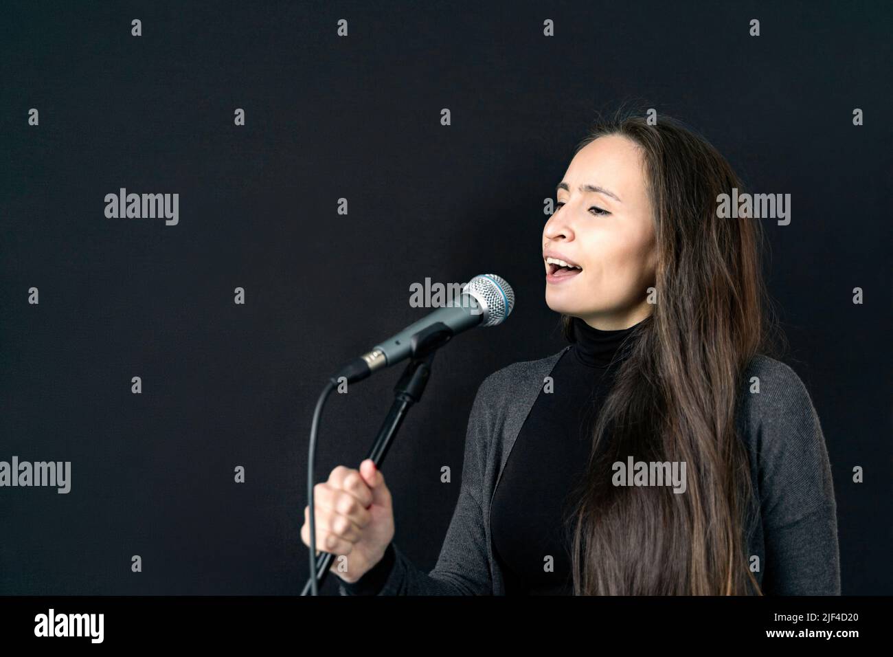 Young Asian or Caucasian woman holding mic, singing song alone in music ...