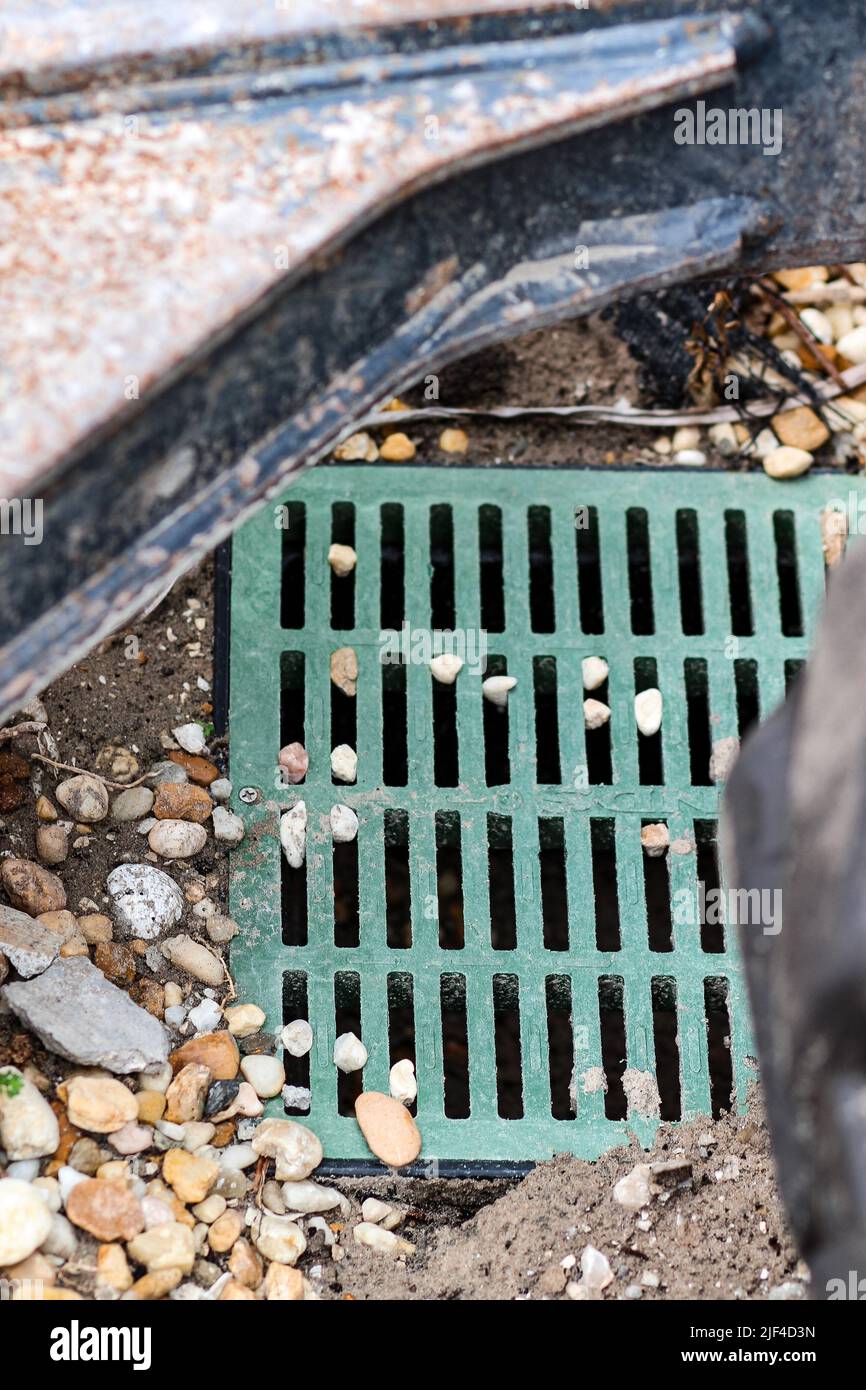 A vertical shot of a green rectangular metal grid cover of the drainage ...