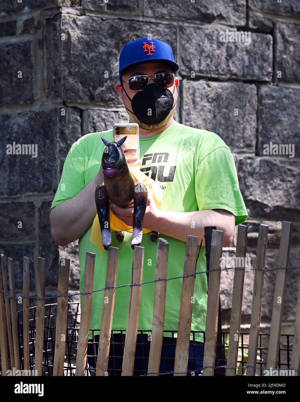 New York, NY, USA. 29th June, 2022. A man and his toy goat wait for the ...