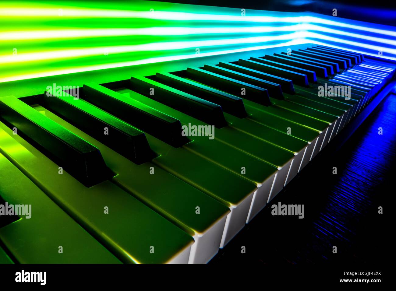 A closeup of the piano keyboard illuminated by green and blue neon ...