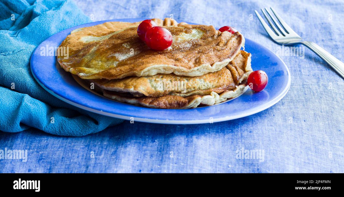 Straight on view of a stack of Banana Pancakes topped with cherries and ...