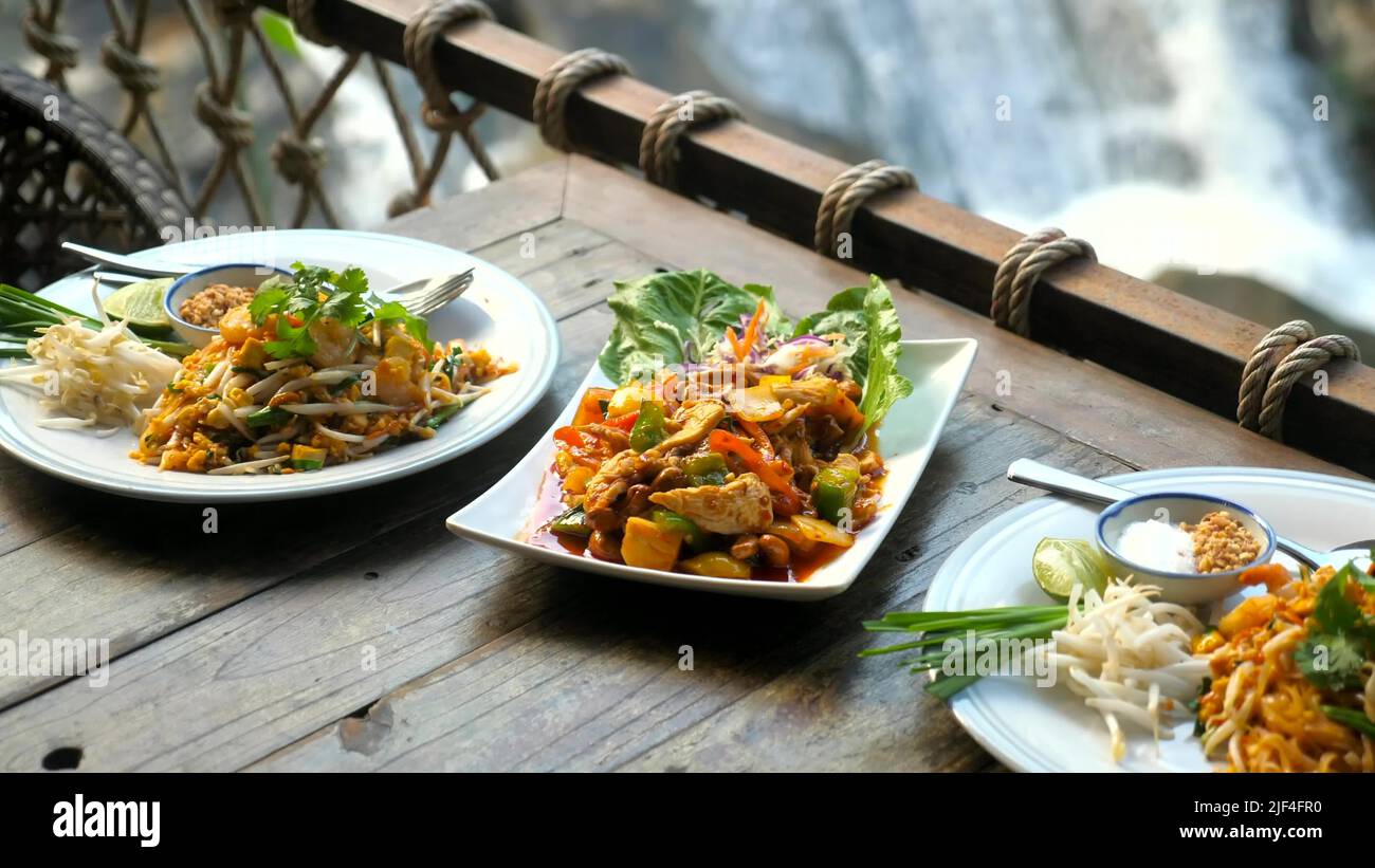 Traditional thai food in outdoor cafe with nature waterfall background ...