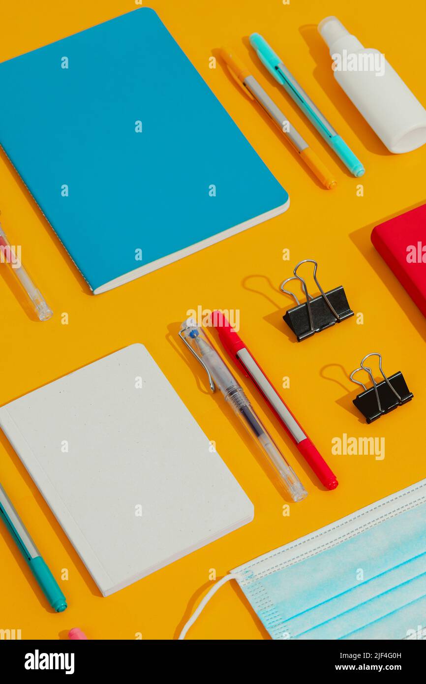 Colorful notepads, pens and hand sanitizer on orange table Stock Photo ...