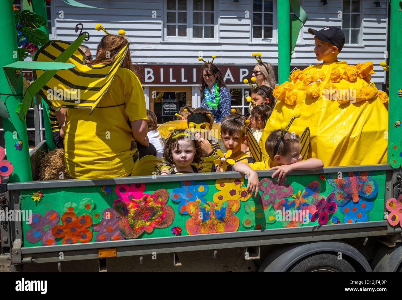 Children dressed in yellow costumes sit on a parade float during ...