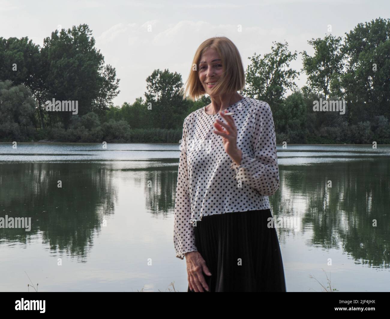 female pensioner having fun and smoking a cigarette in a park - aging ...