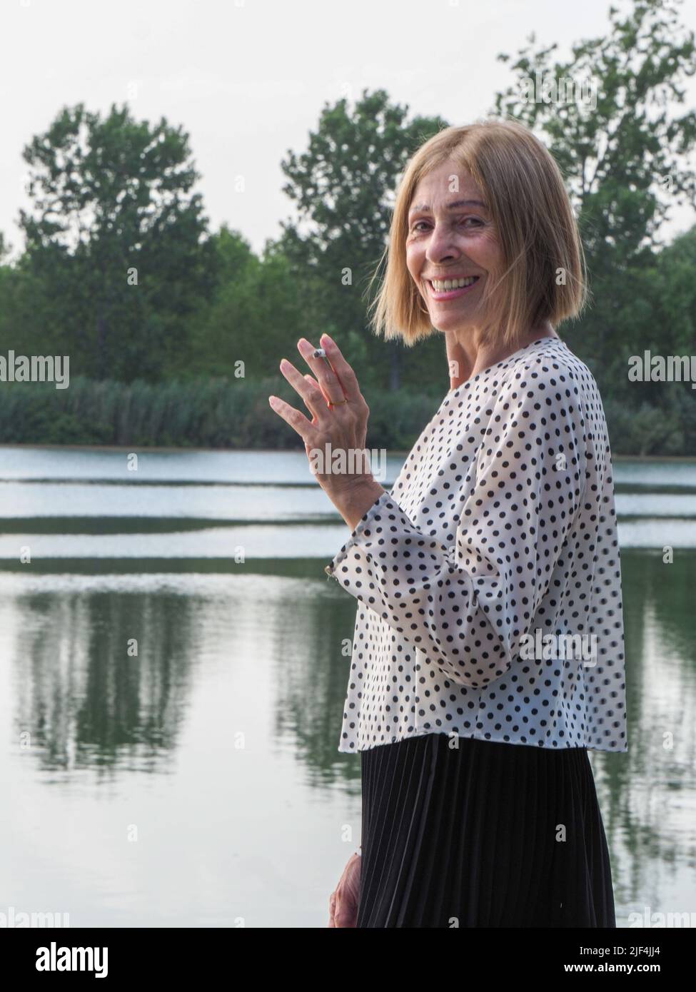 female pensioner having fun and smoking a cigarette in a park - aging ...