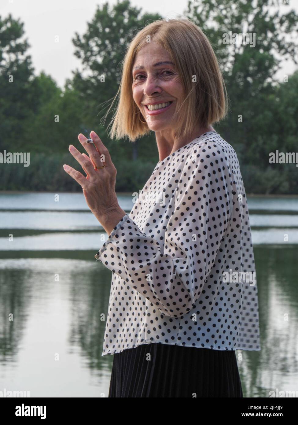 female pensioner having fun and smoking a cigarette in a park - aging ...