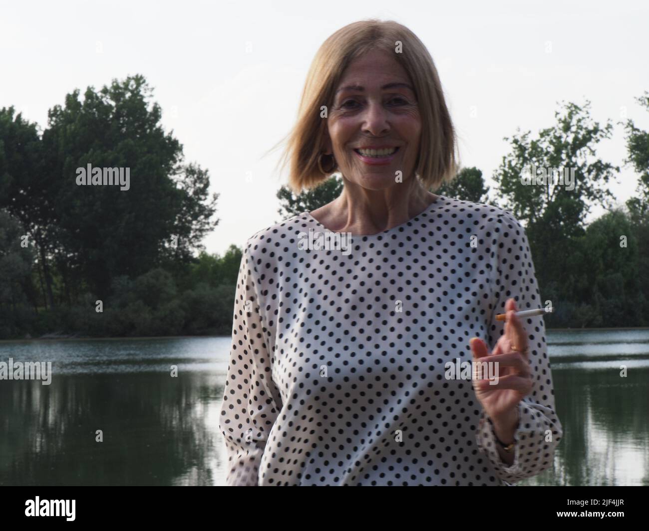 female pensioner having fun and smoking a cigarette in a park - aging ...