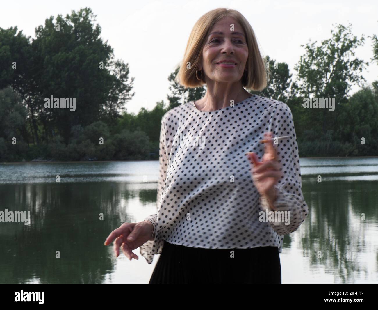 female pensioner having fun and smoking a cigarette in a park - aging ...