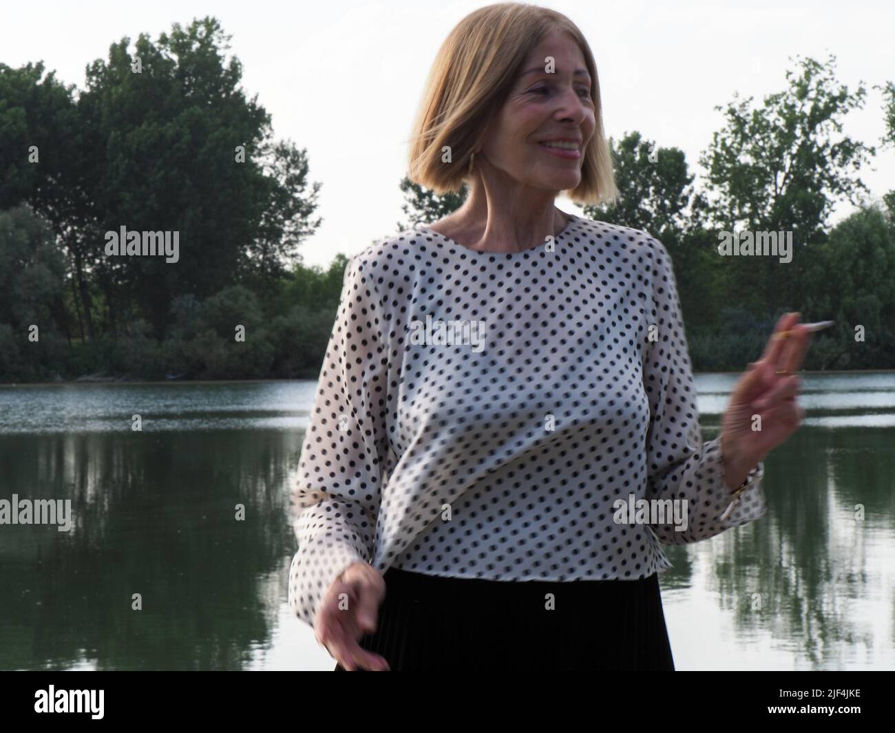 female pensioner having fun and smoking a cigarette in a park - aging ...