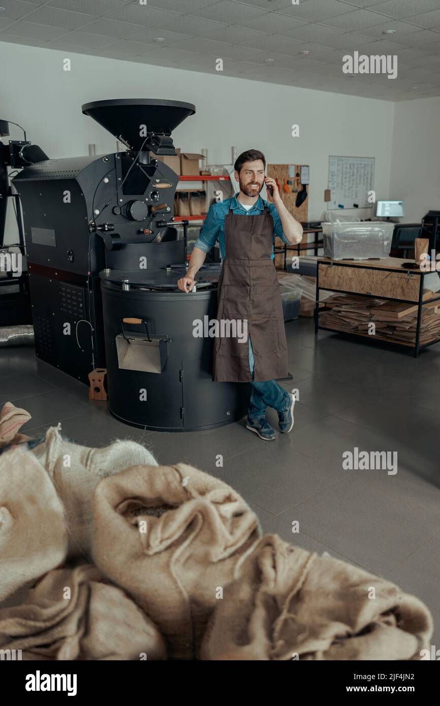 Business owner of coffee factory talking phone on background of coffee ...