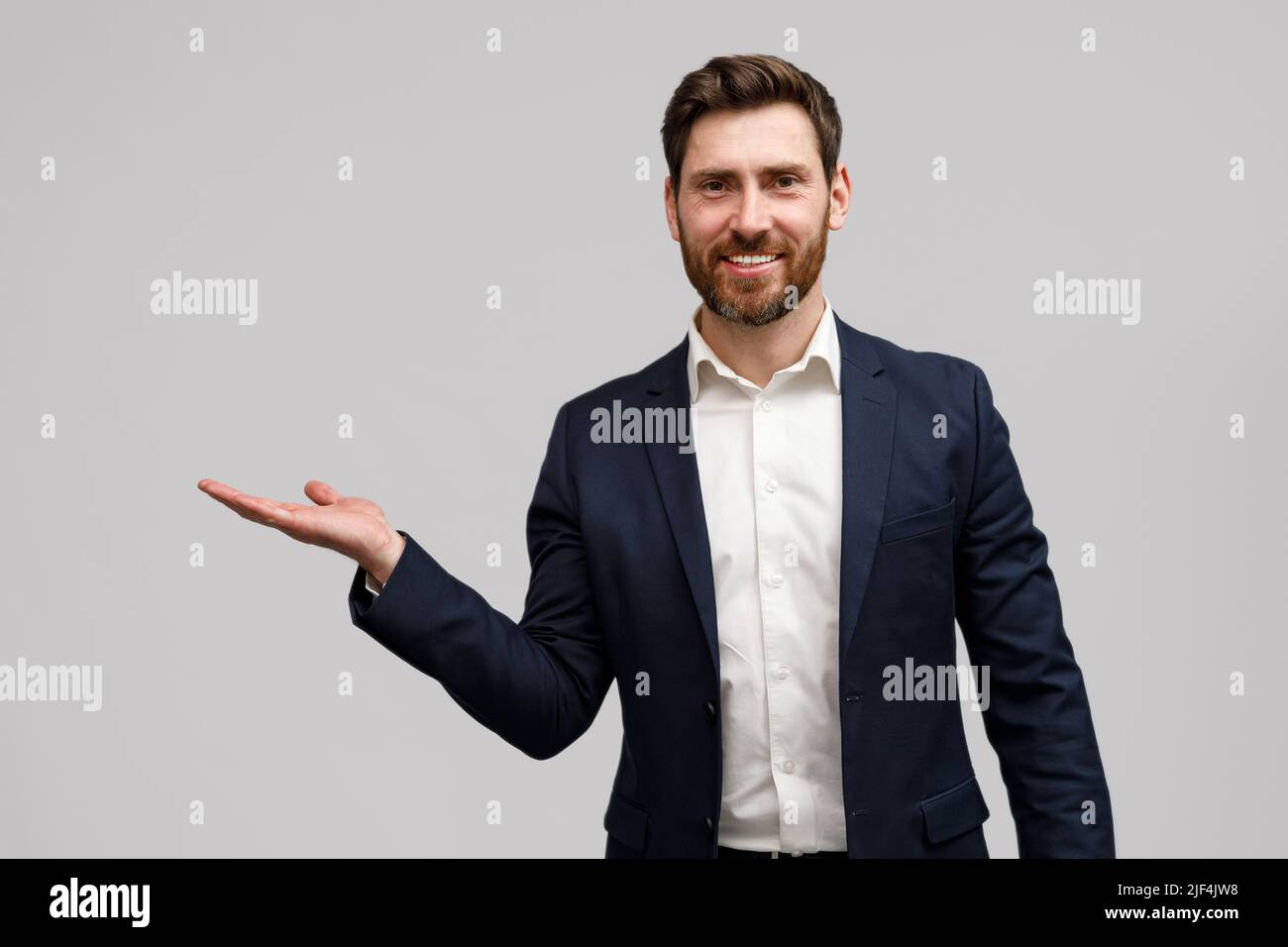 Smiling Businessman looks to camera and points on something with his ...