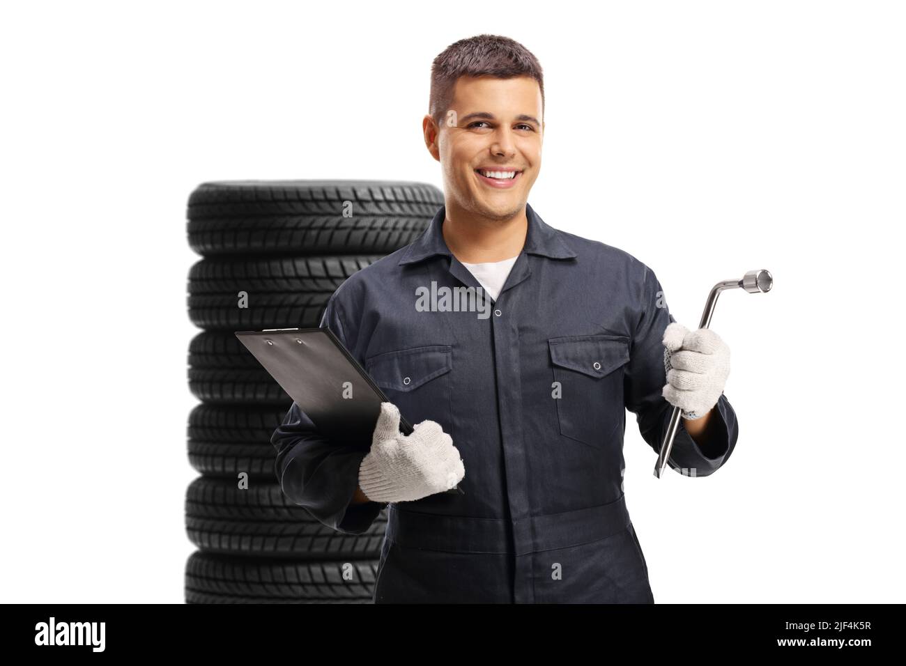 Auto mechanic worker holding tools in front of vehicle tires in a pile ...
