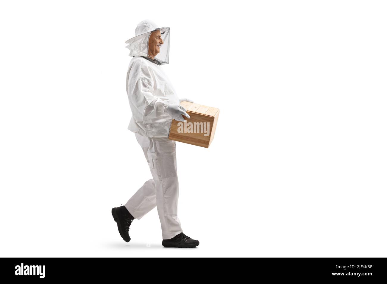 Full length profile shot of a bee keeper in a uniform holding a wooden ...
