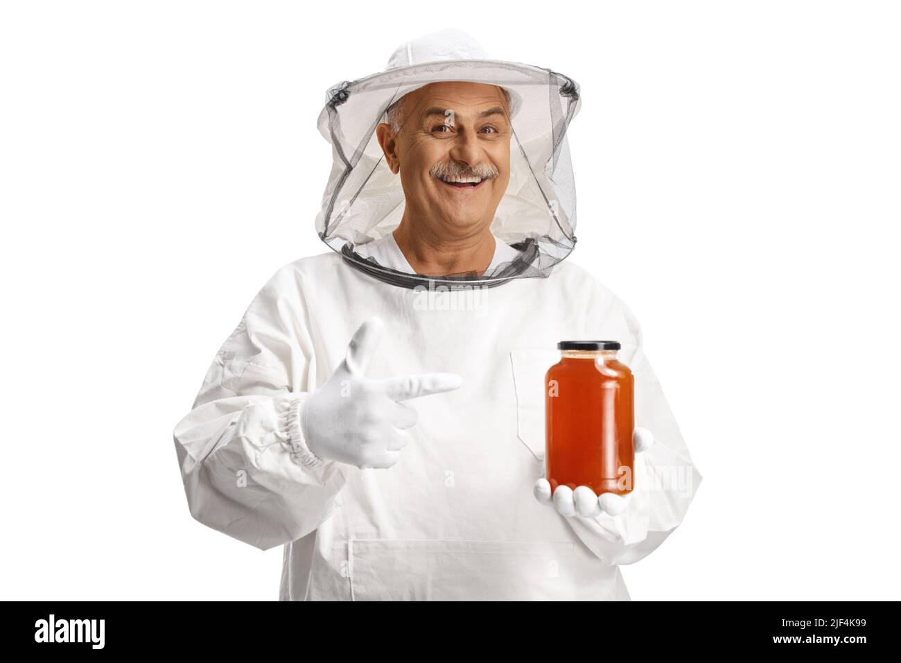 Mature male bee keeper in a uniform holding a jar of honey and pointing ...