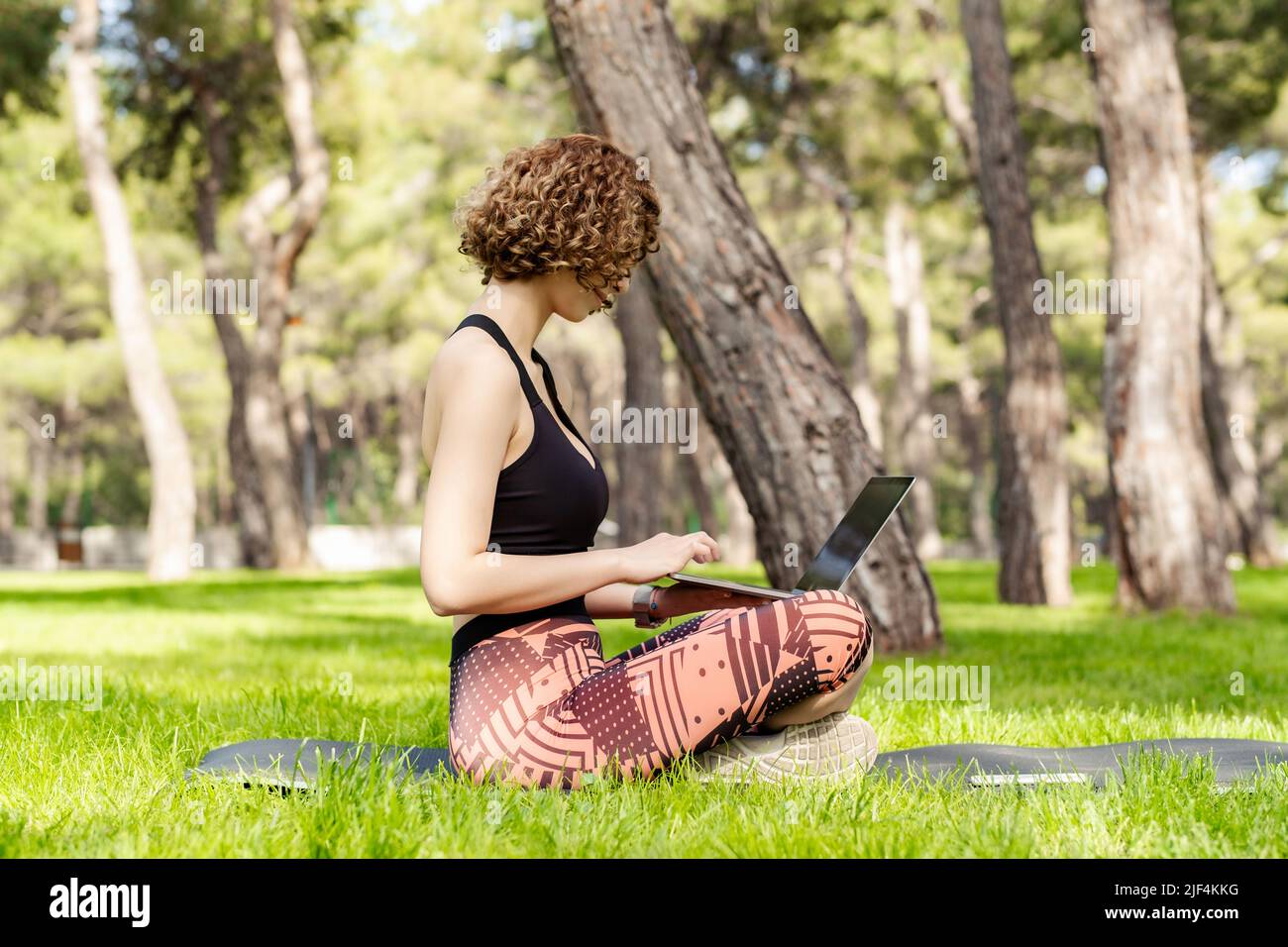 Side view of cheerful woman wearing black sports bra standing on city ...
