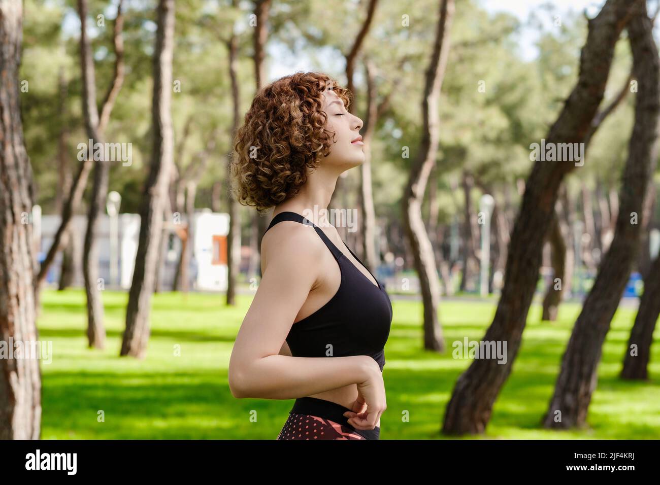 Side view of cute sportive woman wearing black sports bra standing on ...