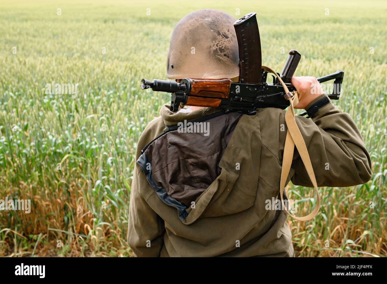 A soldier with a machine gun stands in a field, Ukrainian wheat fields ...