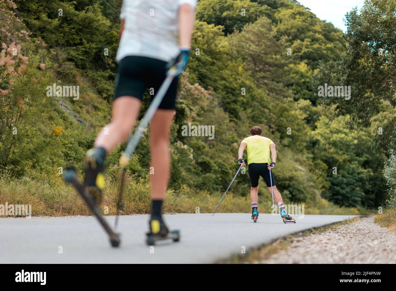 Biathlon workout. Two athletic men training on the roller ski at ...