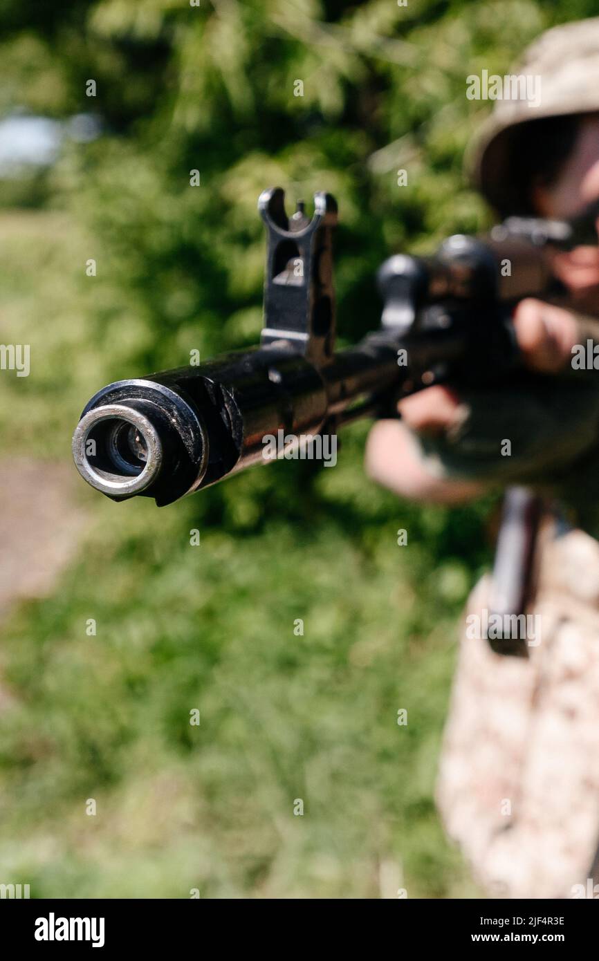 A soldier with a combat military assault rifles AK 74 stands in a field ...