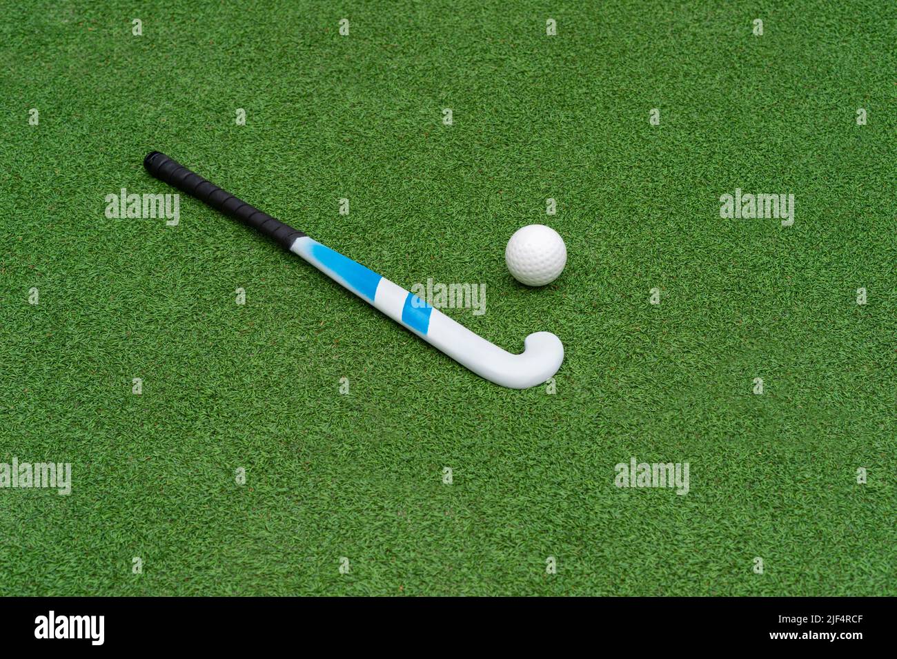 Field hockey stick and ball on green grass. Horizontal sport theme ...
