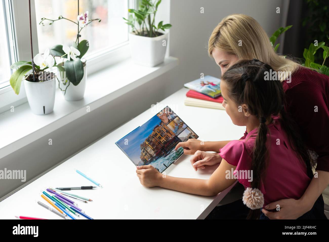 Happy teacher and student girl sitting at working desk in classroom ...