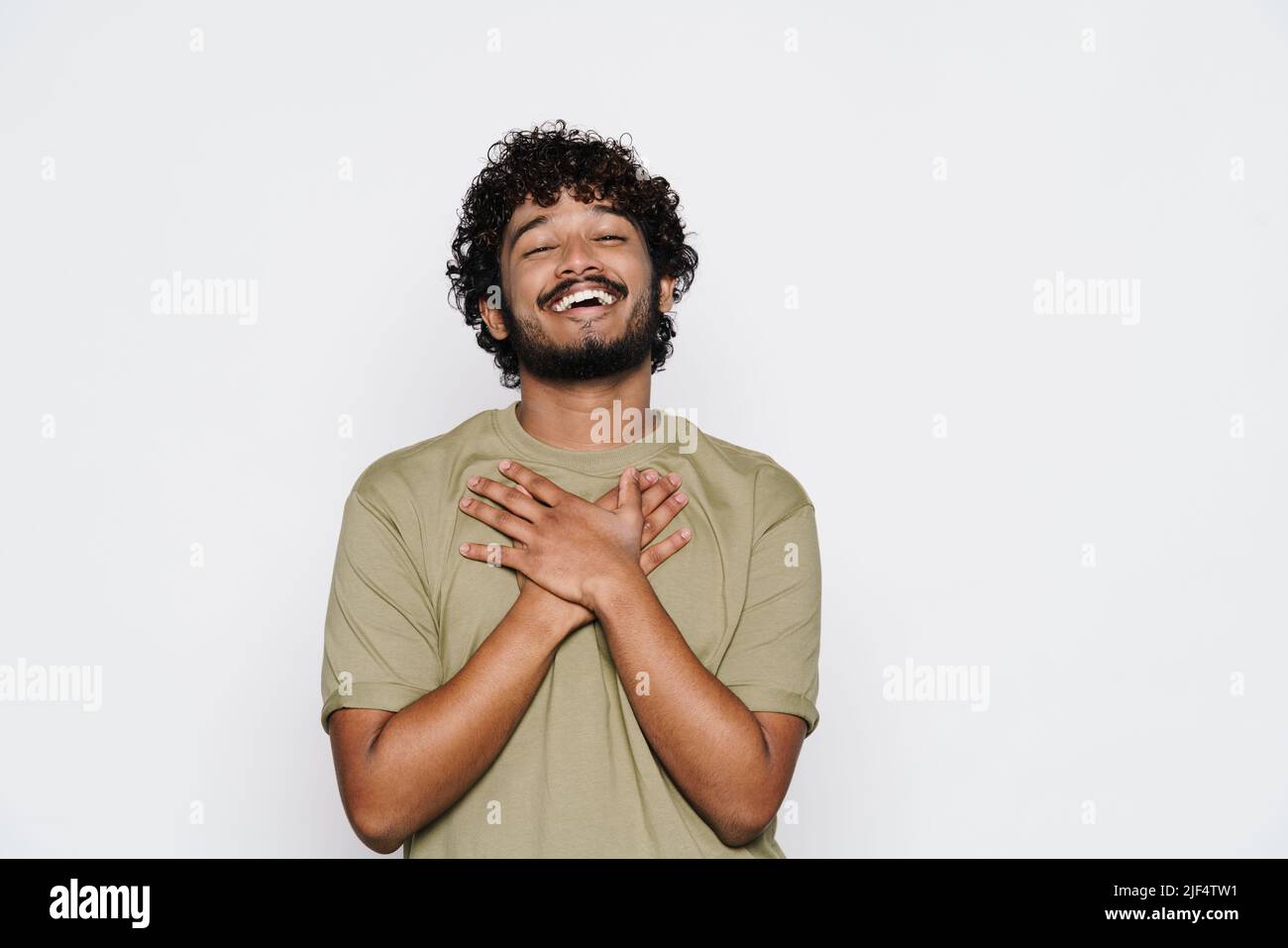 Young middle eastern man smiling and holding hands on his chest ...