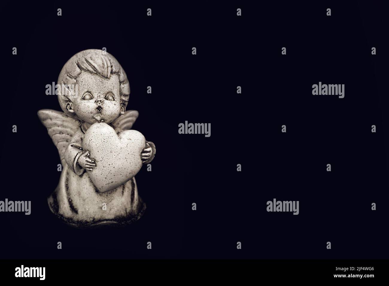 Sympathy card with angel holding a heart isolated on black background ...