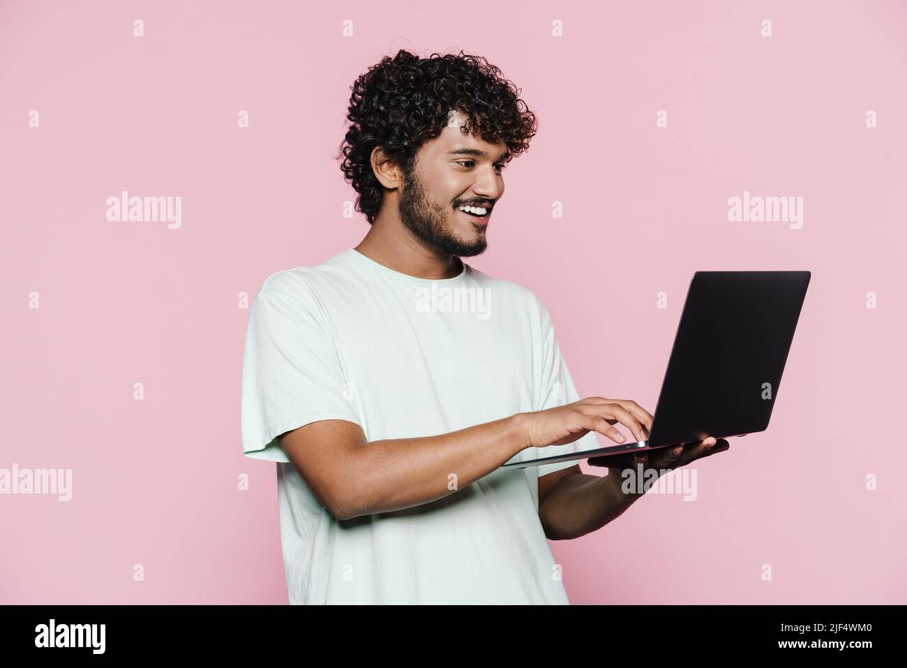 Young middle eastern man smiling while posing with laptop isolated over ...