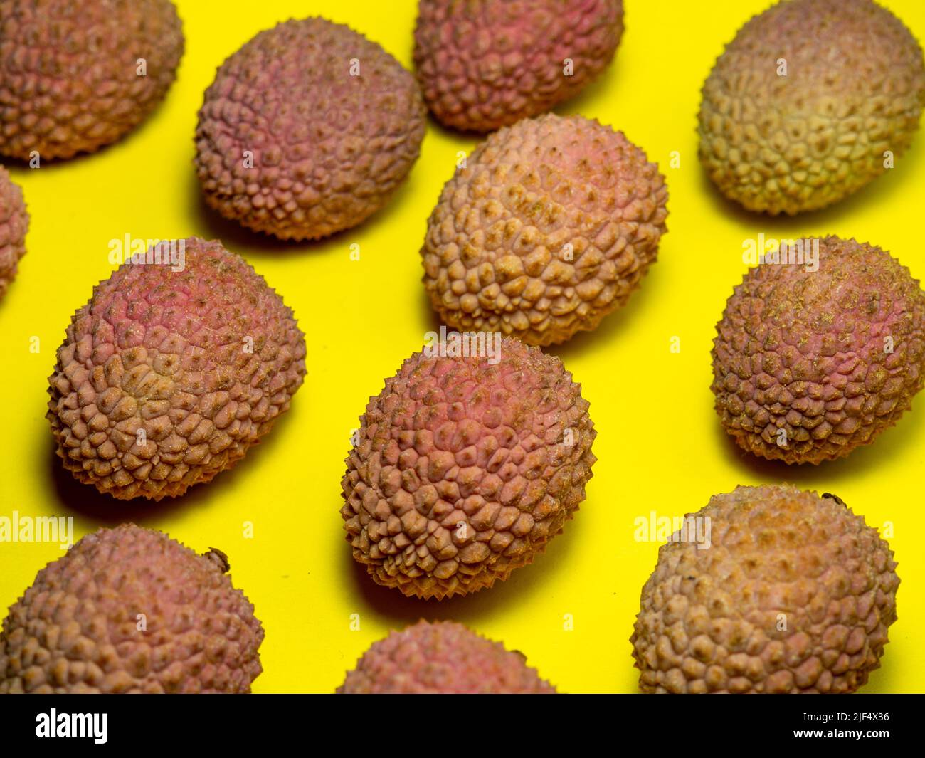 Lychee on the table. Chinese plum on a yellow background. Ripe fruit ...