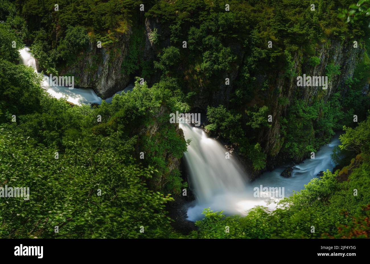An aerial view of small waterfall flowing through lush green rocks ...