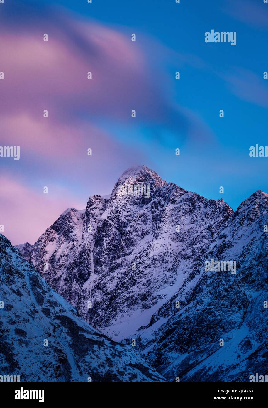 A vertical shot of snowcap rock on pink sunset sky background Stock ...