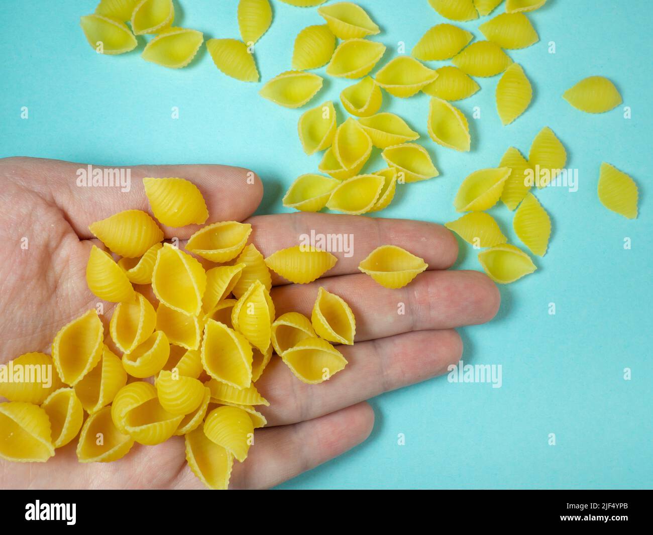 Shell-shaped pasta falls from your hand. Italian food. Cuisine of the ...