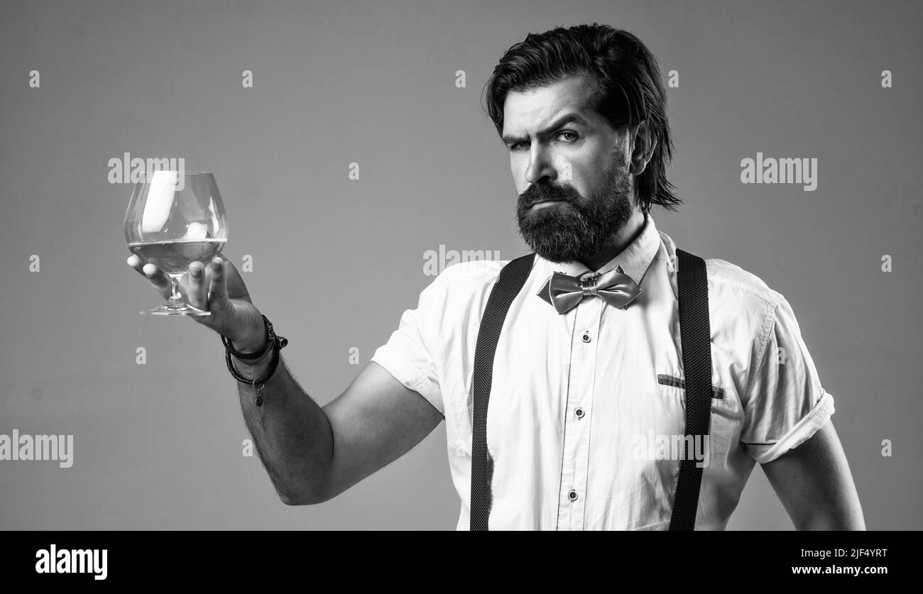 elegant brutal man in formal wear has groomed hair drinking whiskey ...