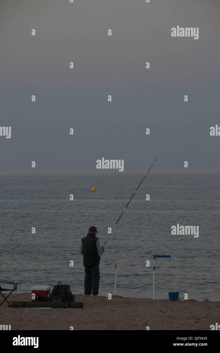 back view, unrecognizable fisherman of fish on the Mediterranean beach ...