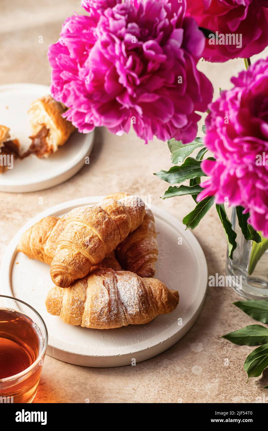 Breakfast with two plates of croissants, tea and peonies flowers on ...