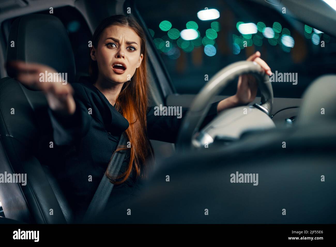 a horizontal photo of a woman sitting behind the wheel of a car with a ...