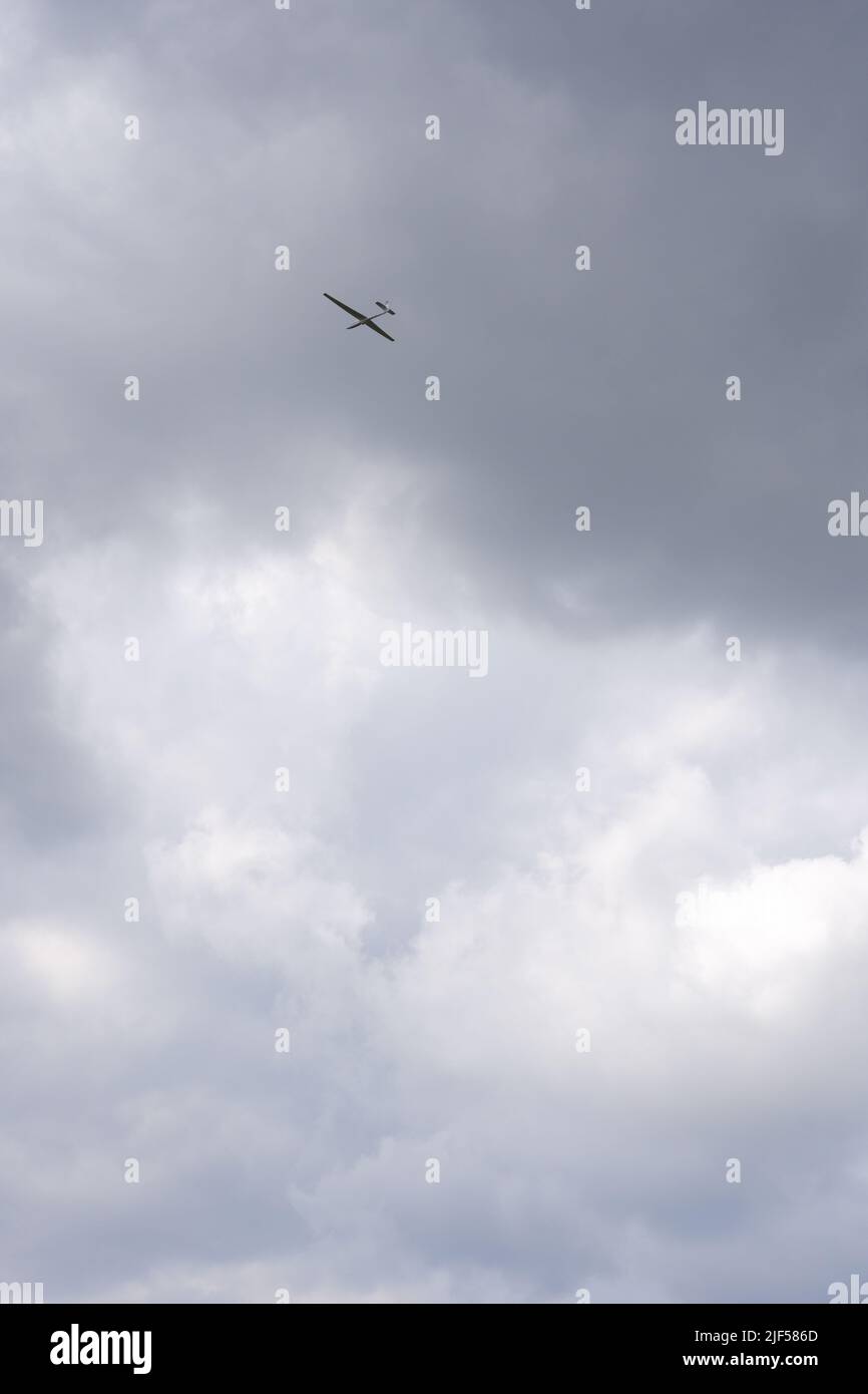 Glider with no engine flies within dark clouds over hills Stock Photo ...