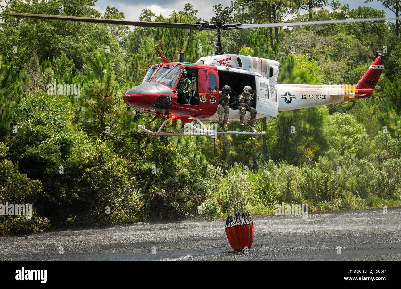 A 413th Flight Test Squadron UH-1 Huey picks up a bucket of water from ...