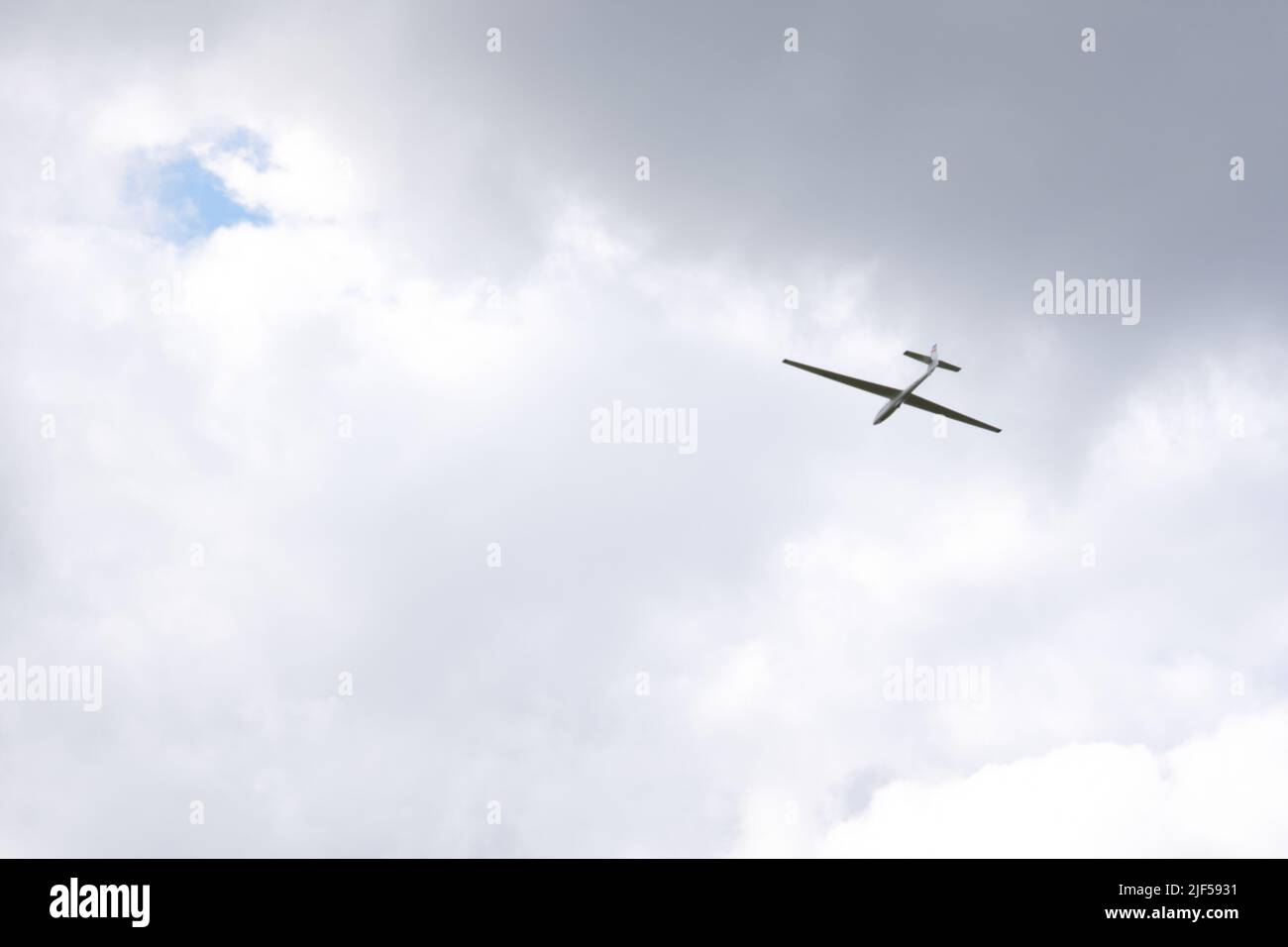 Glider with no engine flies within dark clouds over hills Stock Photo ...