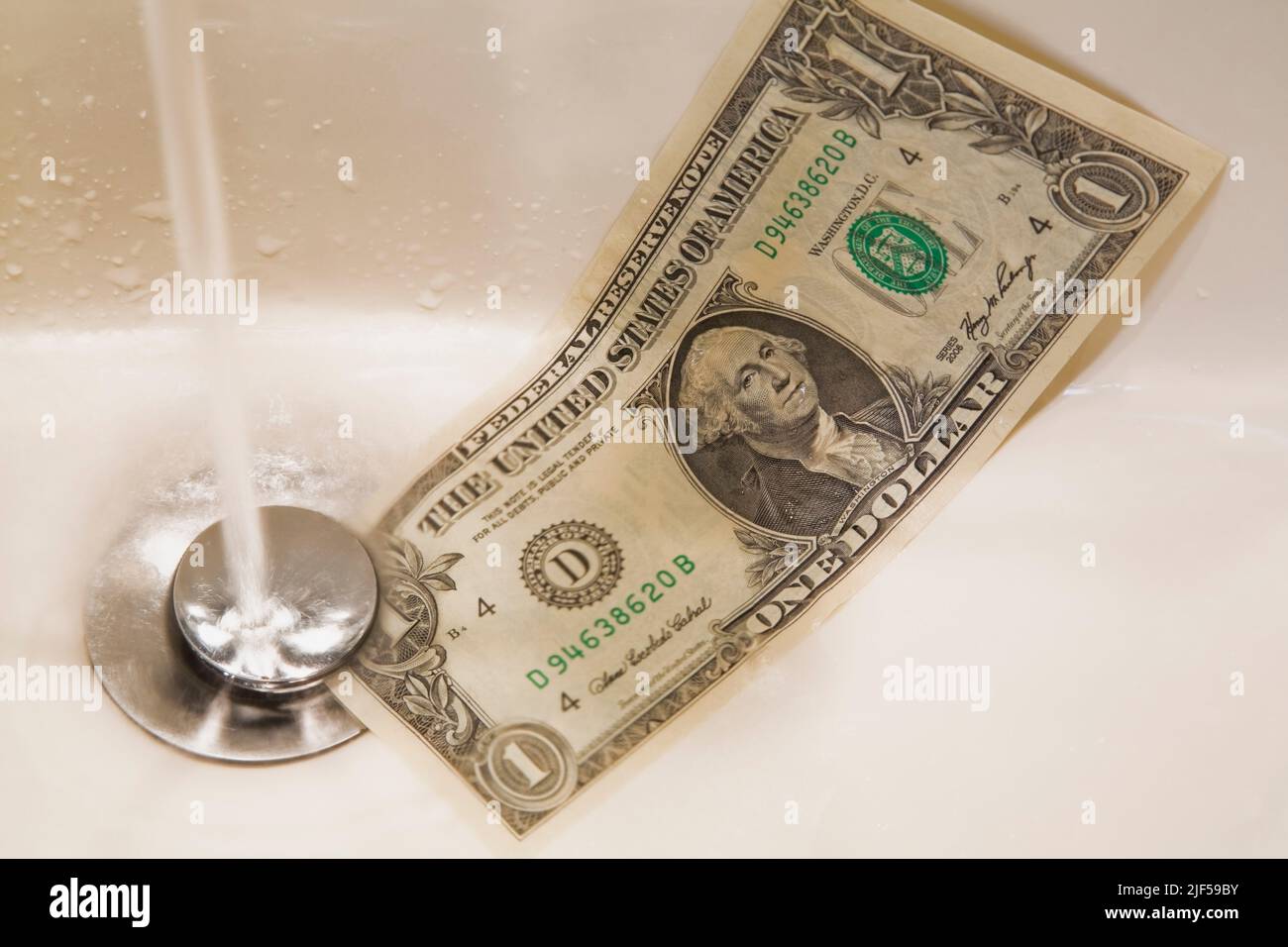 US dollar going down the drain in sink Stock Photo - Alamy