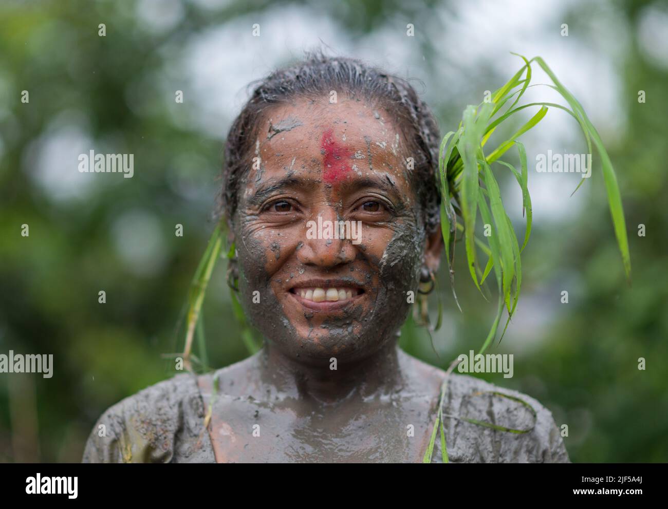 A woman covered in mud smiles in a rice paddy field during National ...