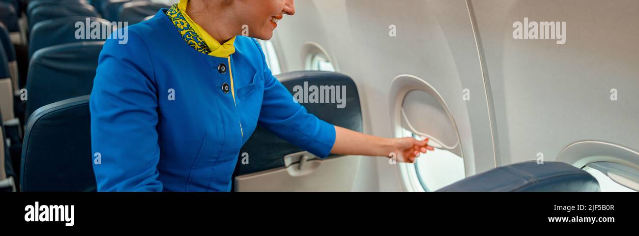 Smiling woman stewardess closing window in airplane Stock Photo - Alamy