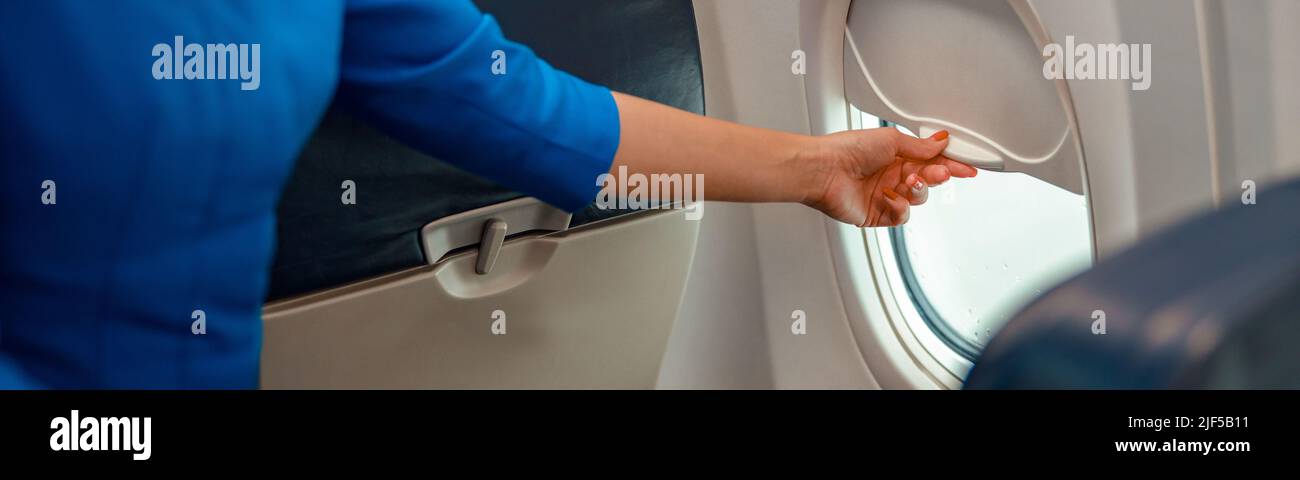 Woman flight attendant closing window in airplane Stock Photo - Alamy