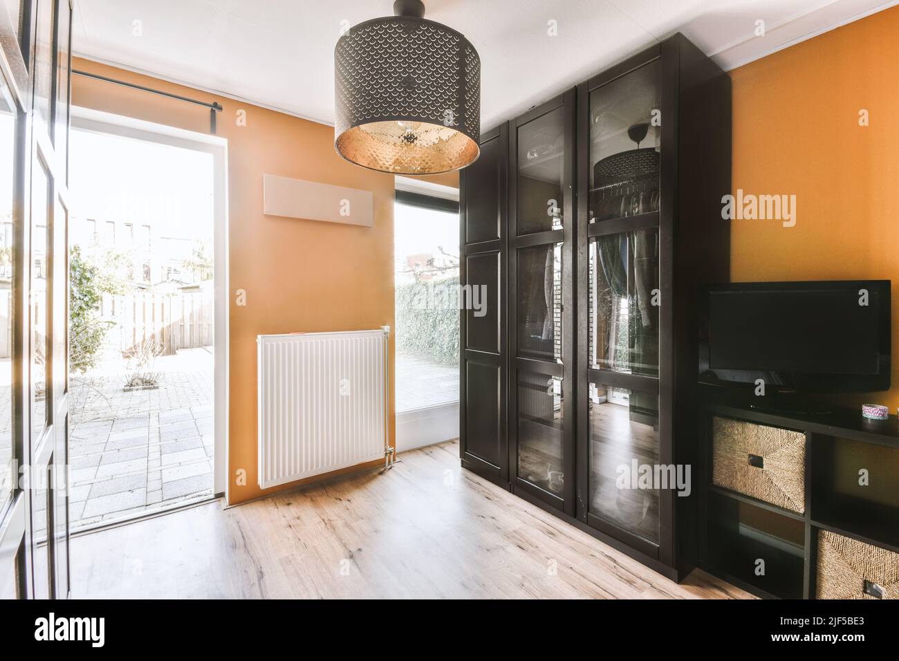 Stylish room with bright, orange walls, wardrobes, TV and access to the ...